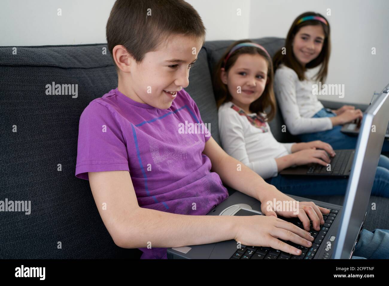 Group of children using laptops while sitting on sofa at home Stock ...