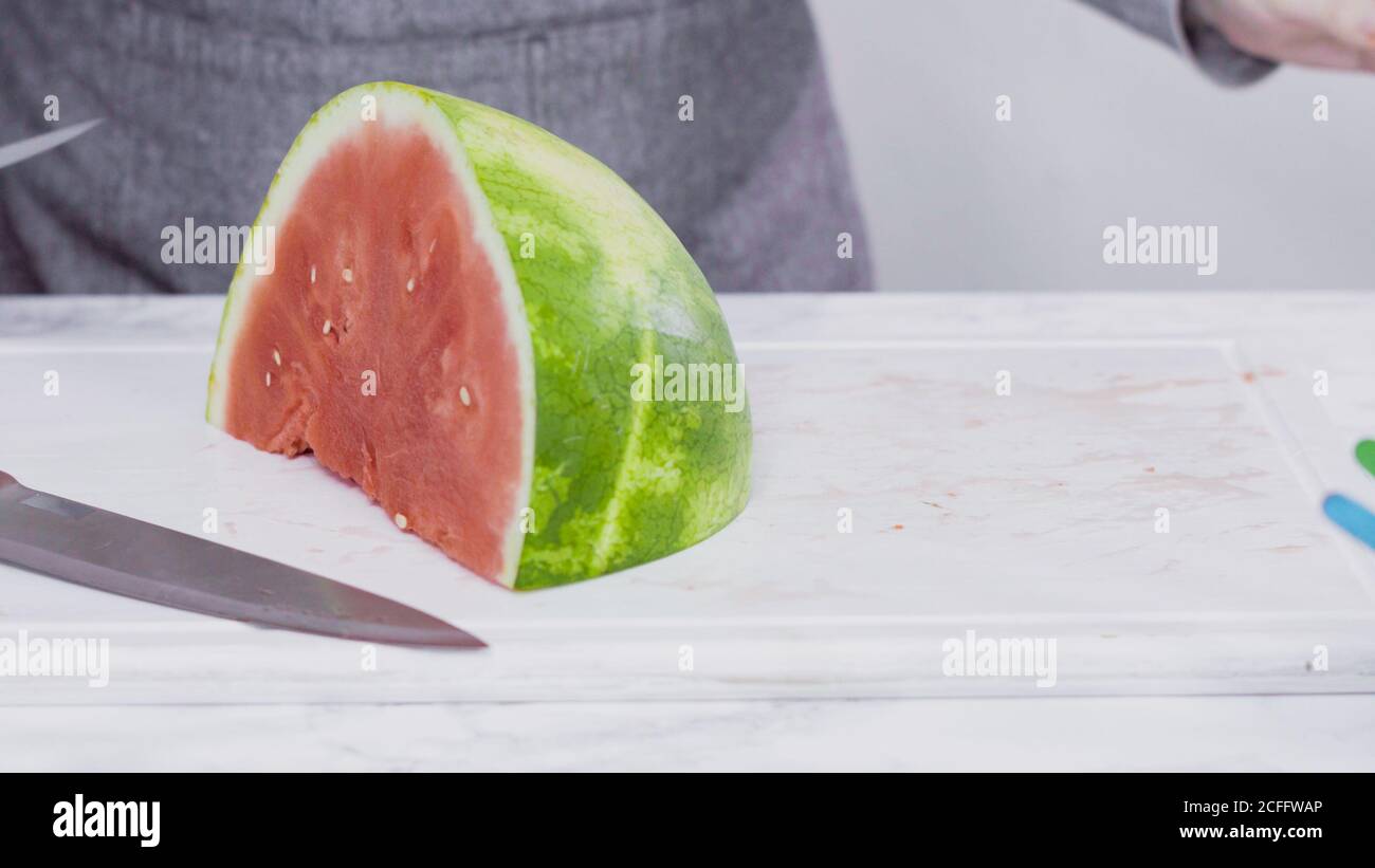 Slicing red watermelon into small pieces on a white cutting board Stock ...