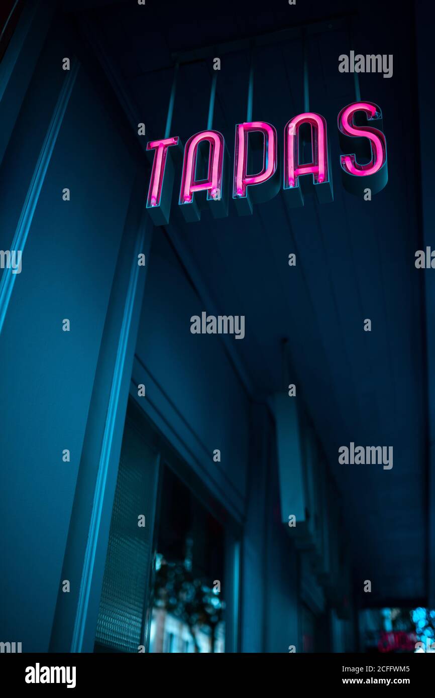 From below pink Tapas sign hanging outside diner in evening on town ...