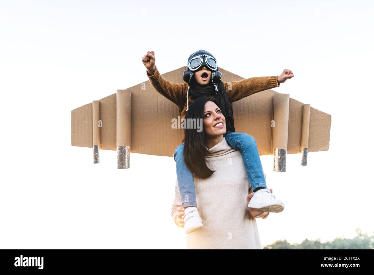 Happy cute boy wearing goggles and cardboard wings while sitting on ...
