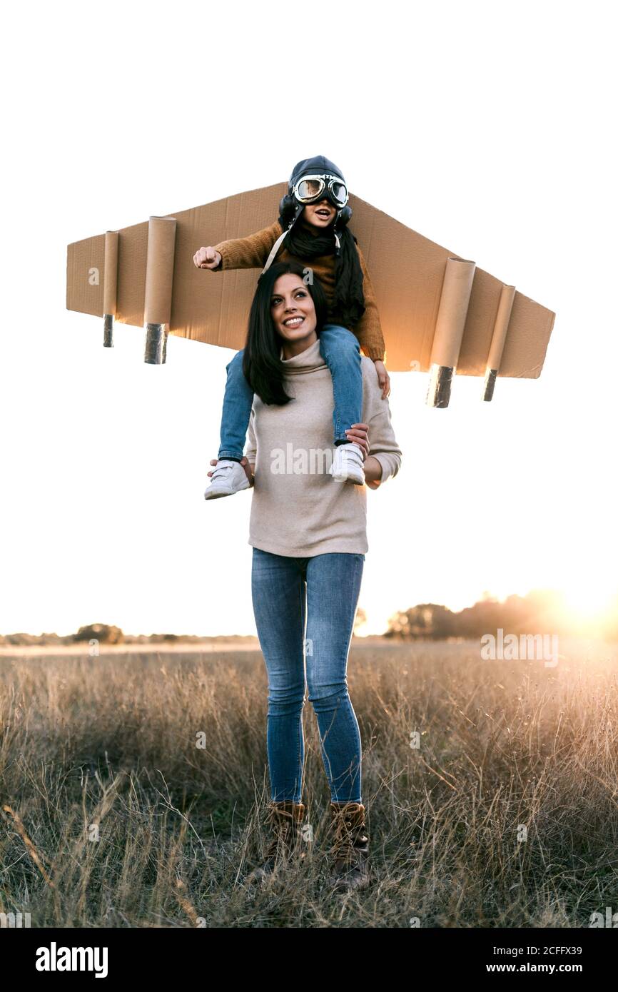Happy cute boy wearing goggles and cardboard wings while sitting on ...