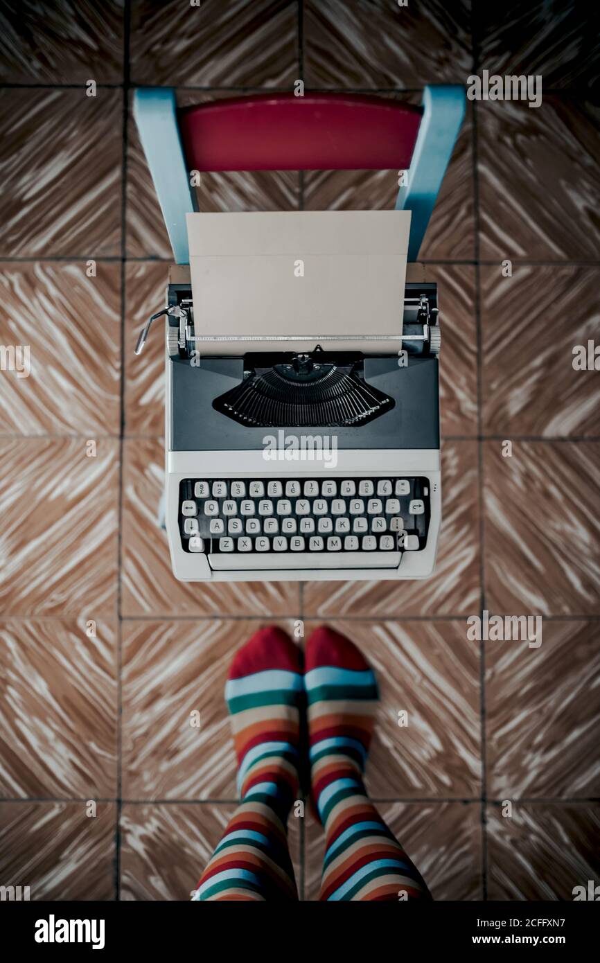 Top view of faceless author in stripped socks standing near shabby ...