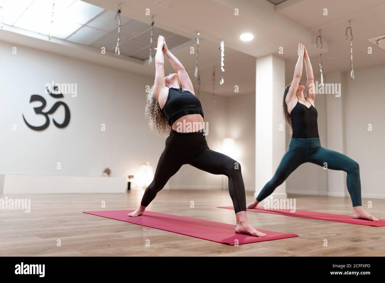 Balanced calm women stretching and raising hands up in warrior one ...