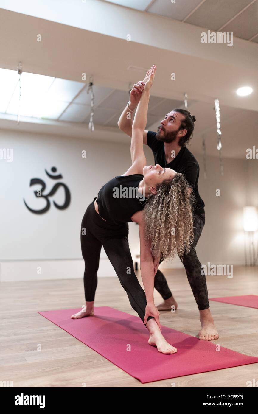 Balanced calm Woman and man teacher helping correcting pose on extended ...