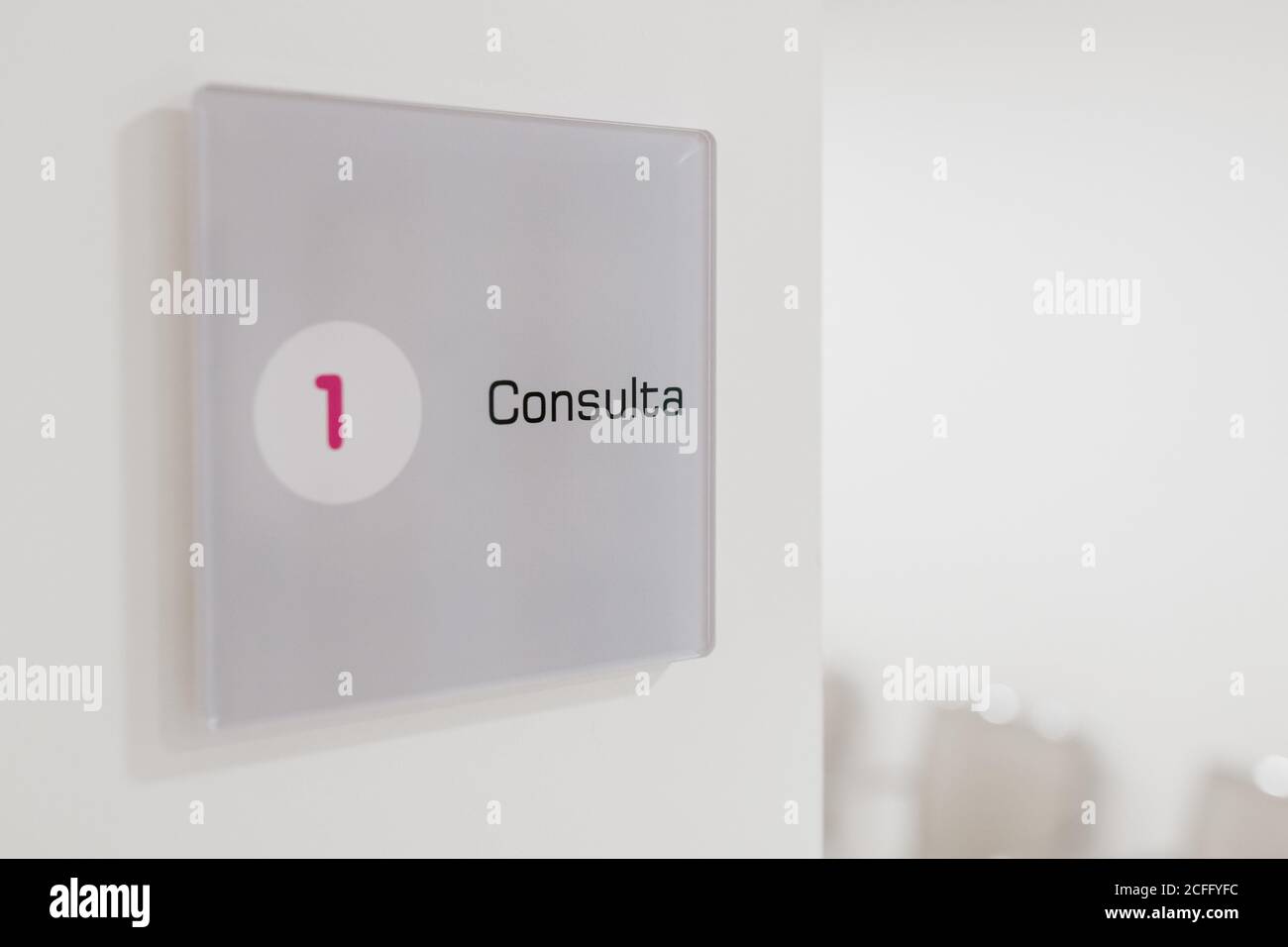 Light grey square sign on white wall indicating number one and word ...