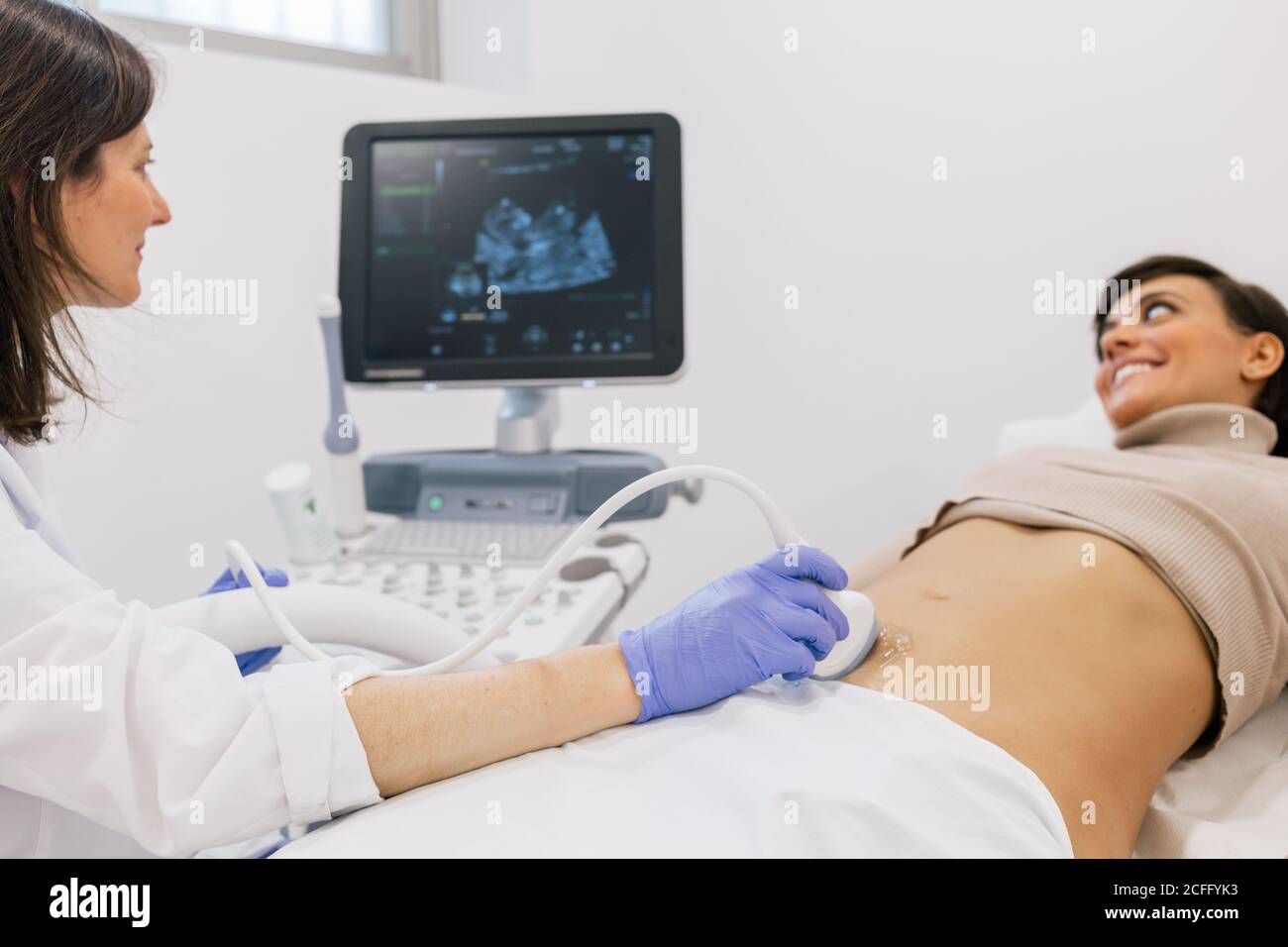 Crop medical practitioner making sonogram to happy pregnant Woman ...
