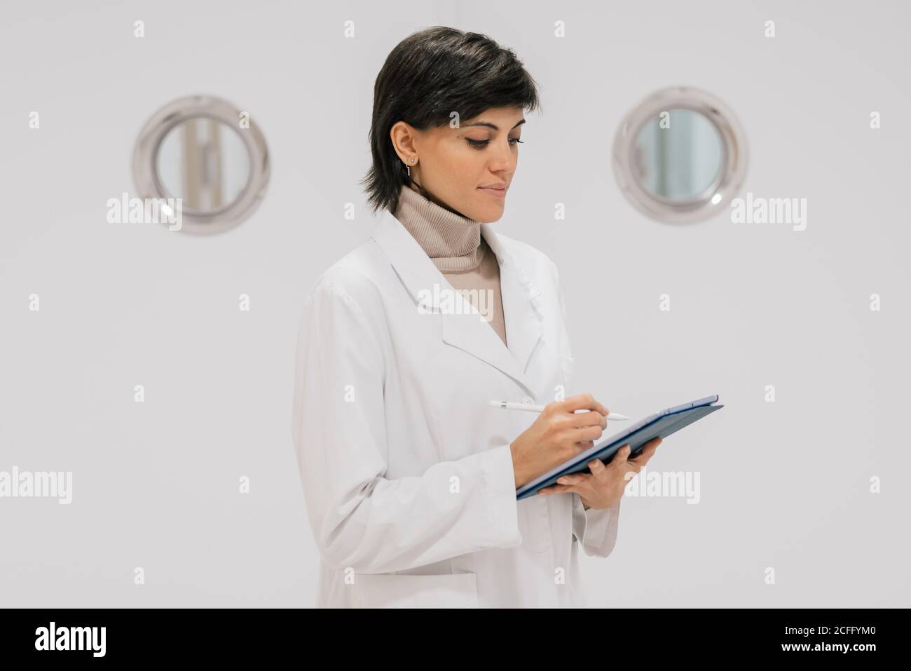 Side view of positive medical practitioner using tablet while standing ...