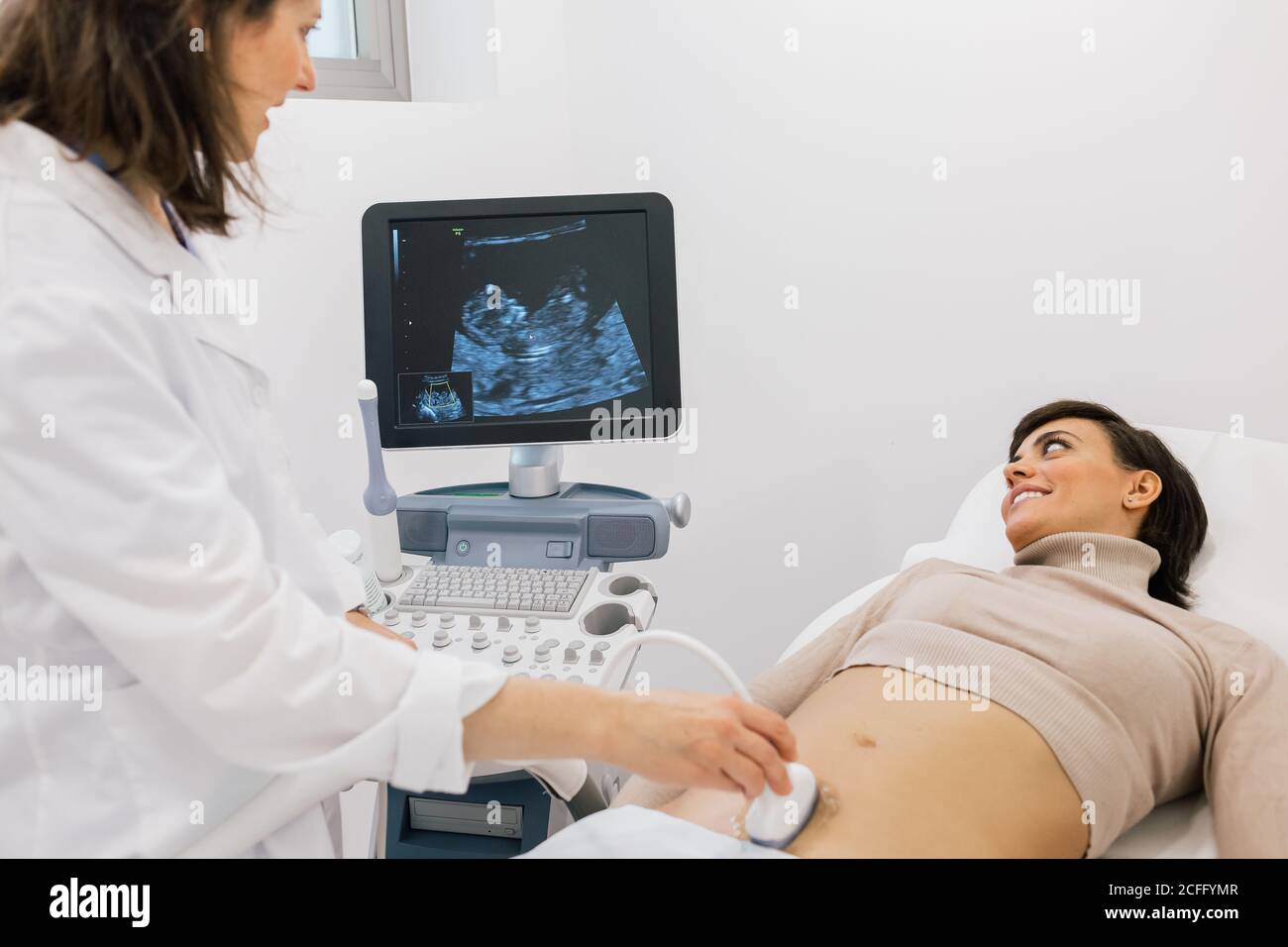 Crop medical practitioner making sonogram to happy pregnant Woman ...