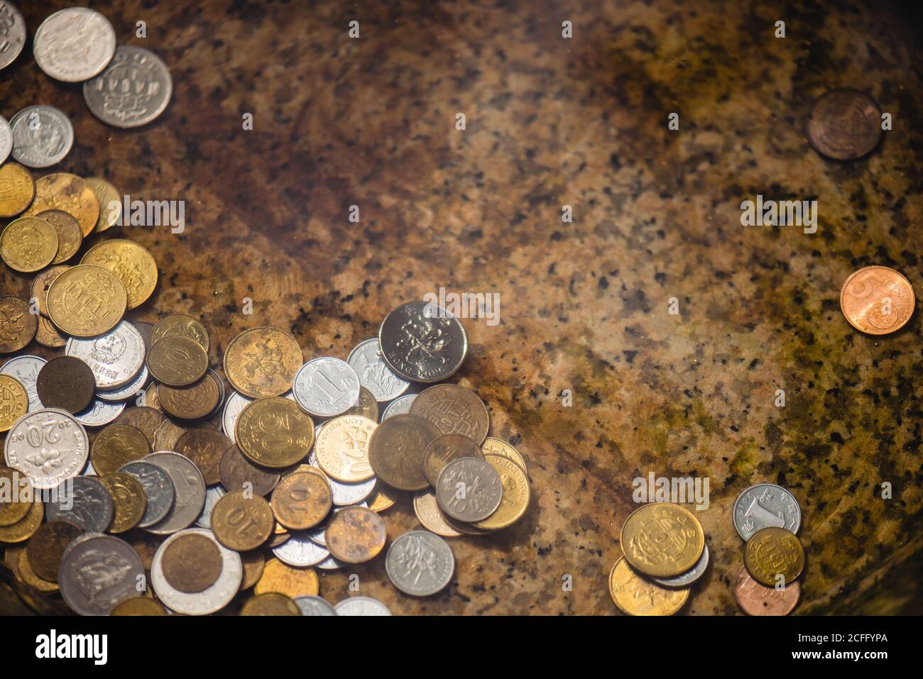From above of shiny various coins on stone surface of fountain under ...