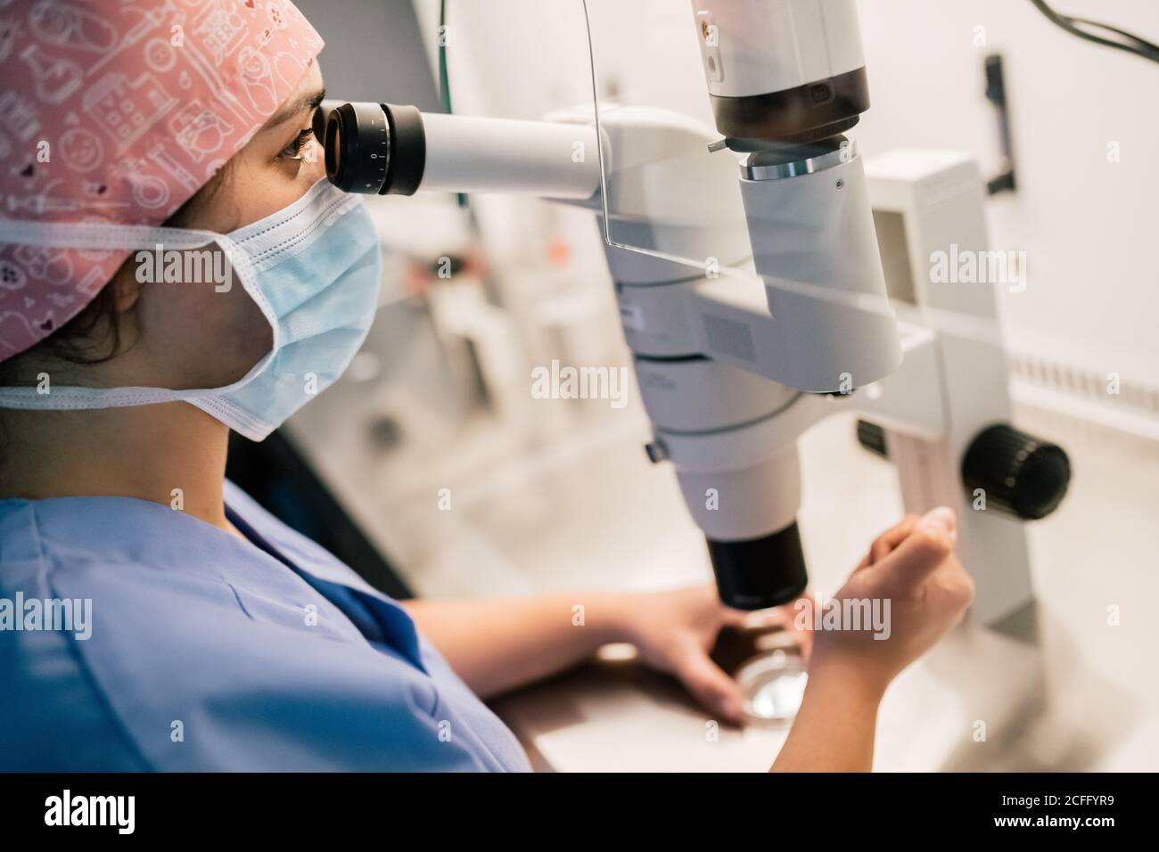 From above doctor in medical mask and uniform injecting ovum on Petri ...