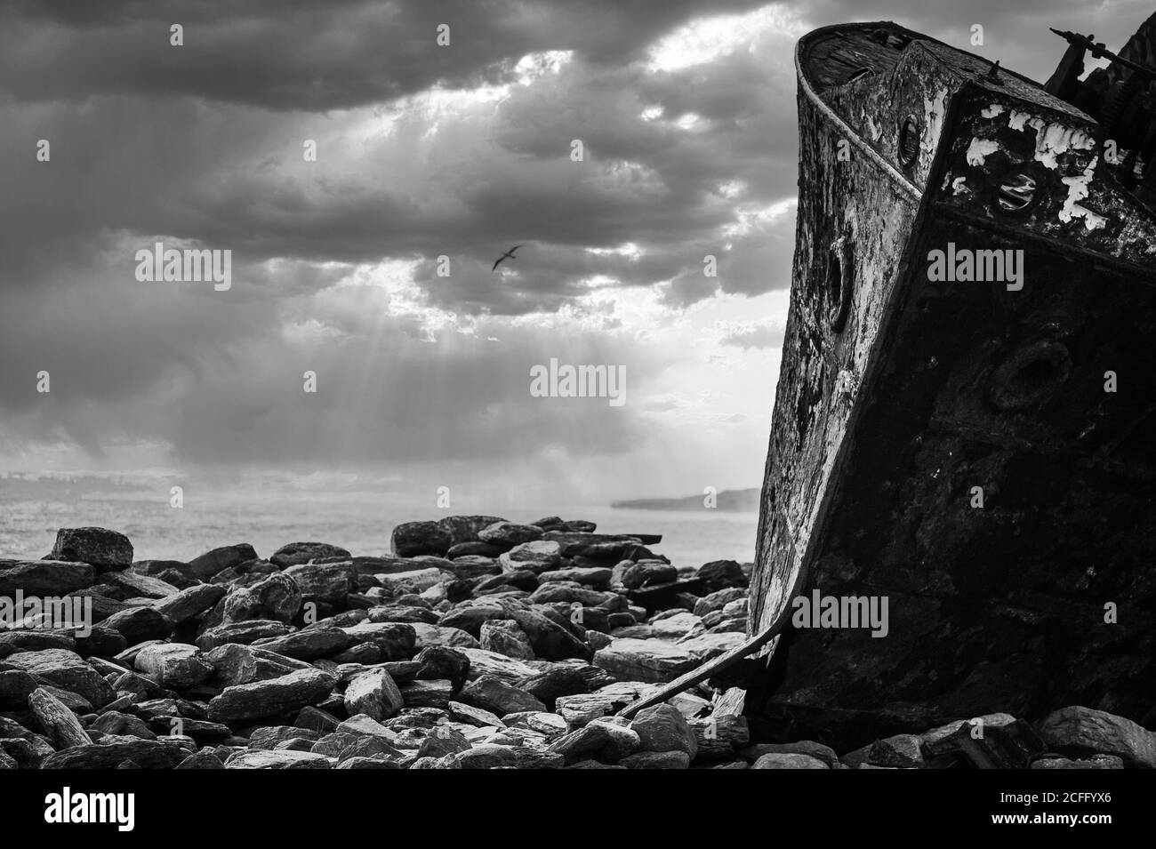Metal rusty wreckage of old ship on empty rocky coast against glowing ...