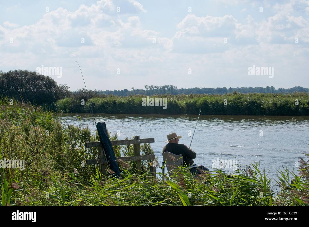 Coarse fishing on the Norfolk Broads Man sitting relaxed on reed bank ...