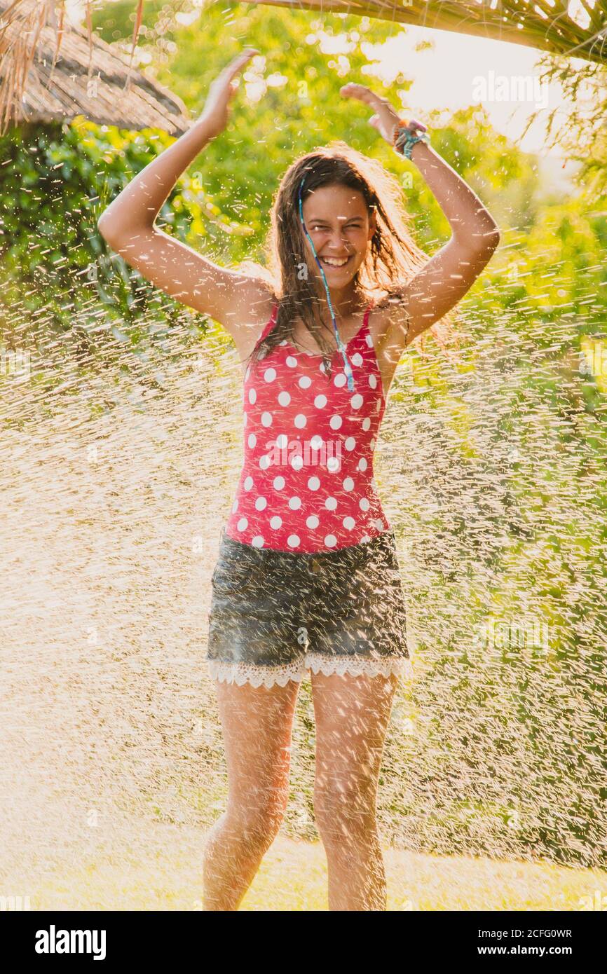 Excited teen girl laughing and playing with jet of clean water while ...