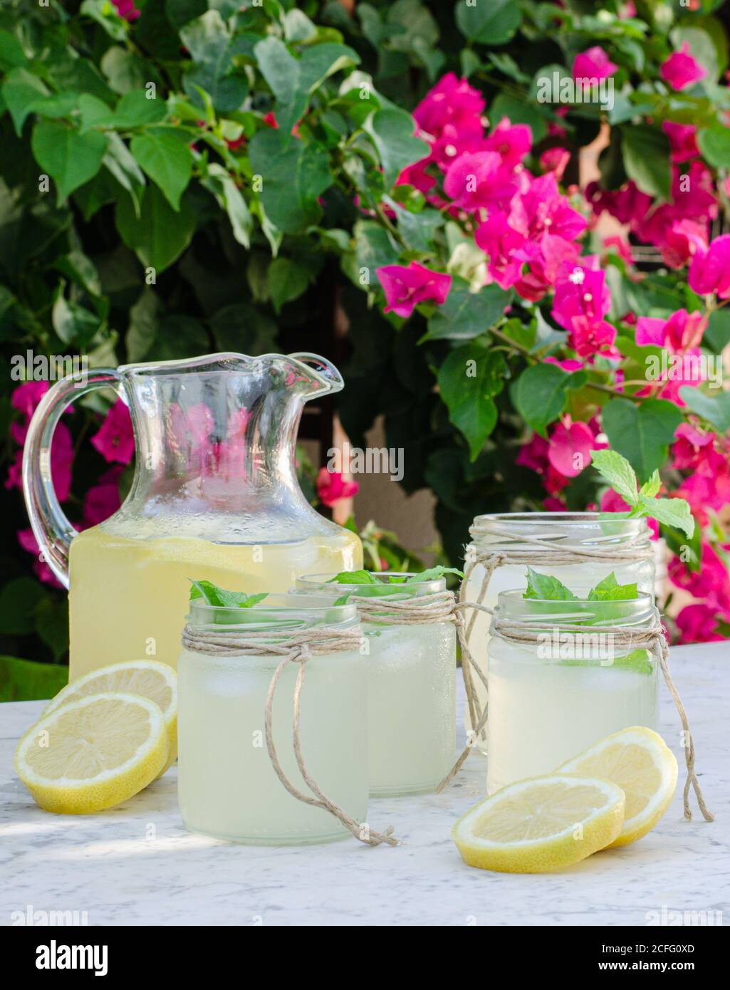 Glass jar with fresh cold lemonade placed on marble table with slices ...