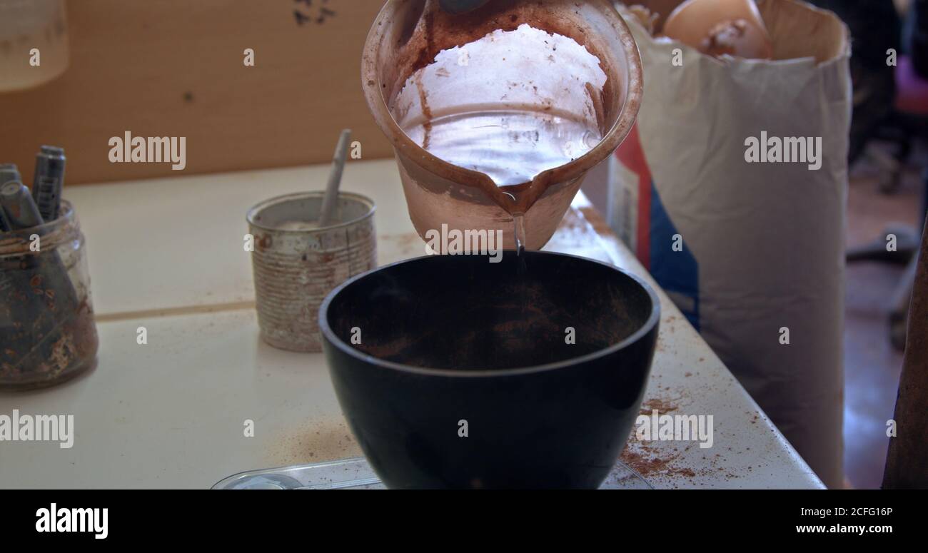 Crop person pouring crystal water from clay pot into black bowl on ...