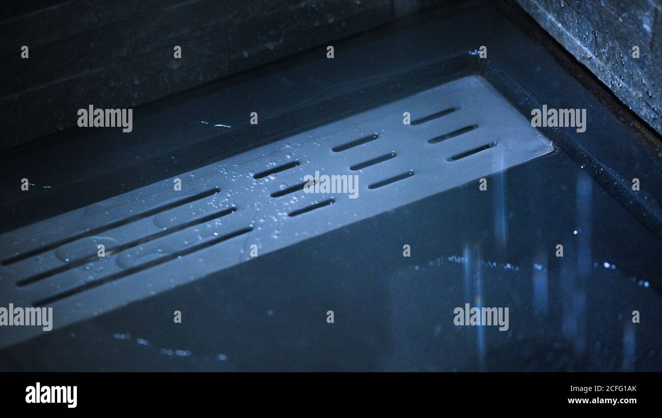 From above streams of water falling on floor and flowing into drain in ...