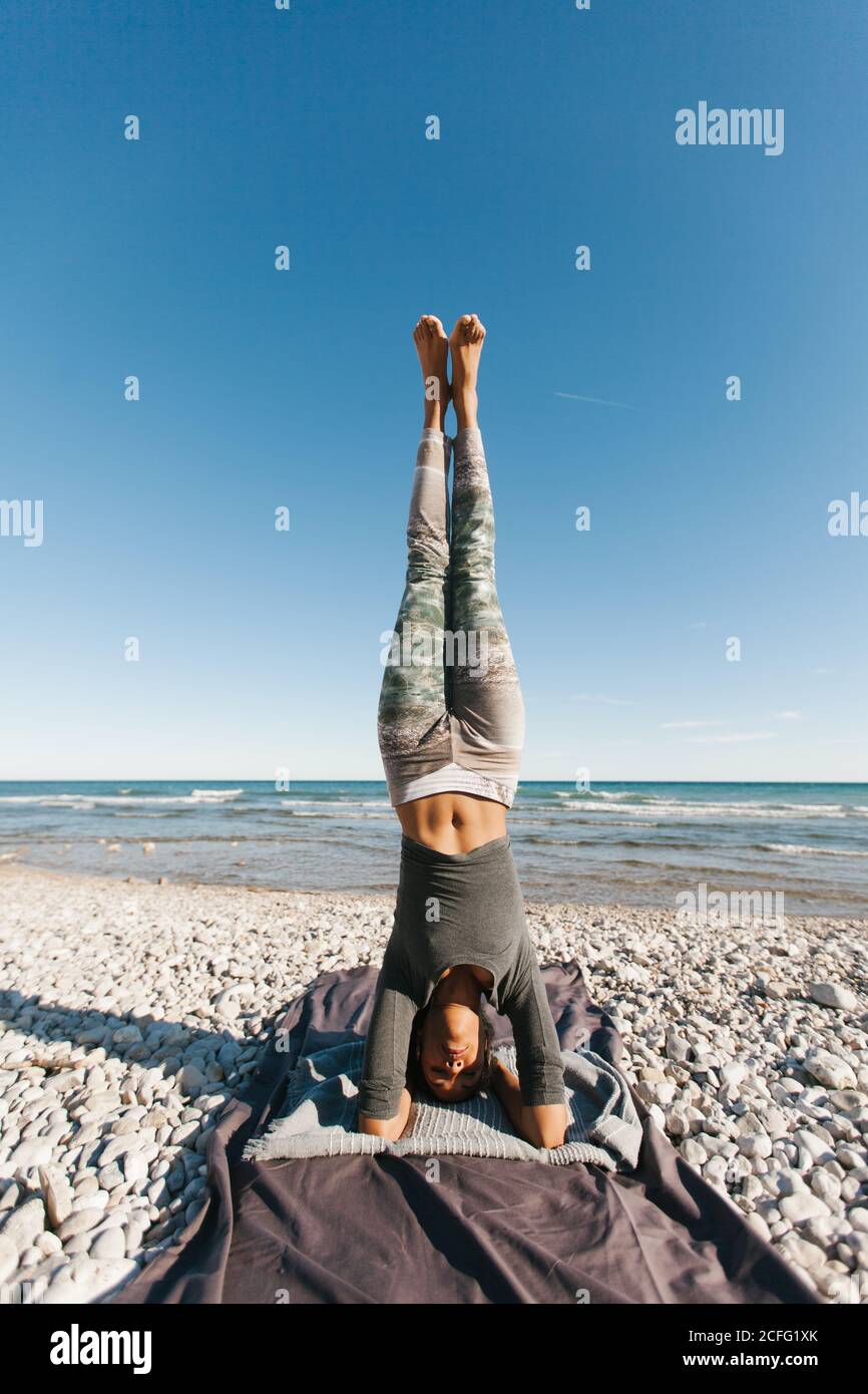 African American attractive young Woman in yoga headstand posture in ...