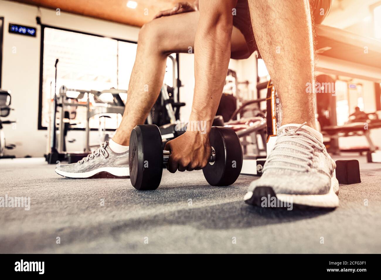 A man pick dumbbell on the floor at fitness gym with sun light Stock ...
