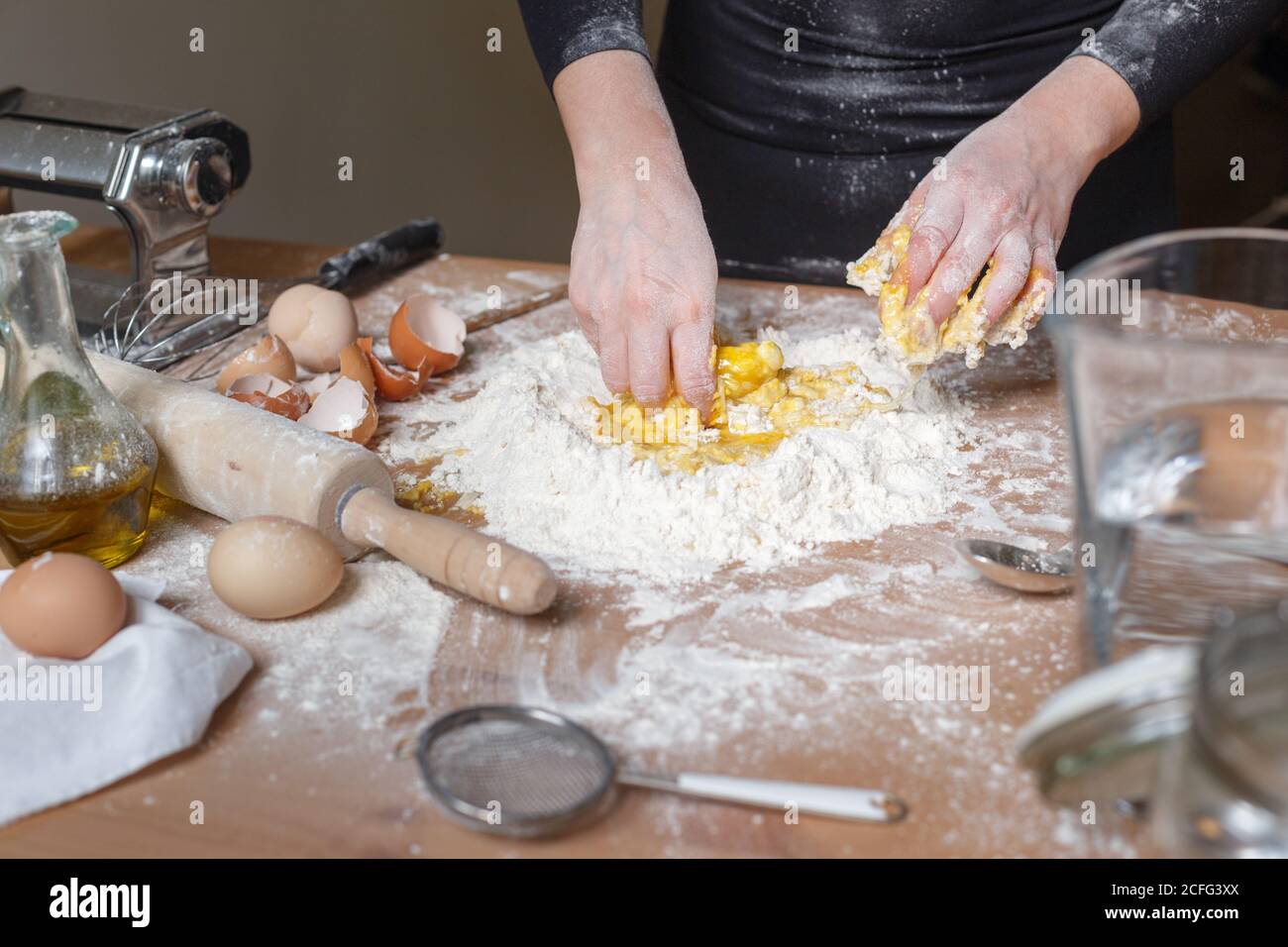 anonymous person in black clothes making recess in flour mass with hand ...