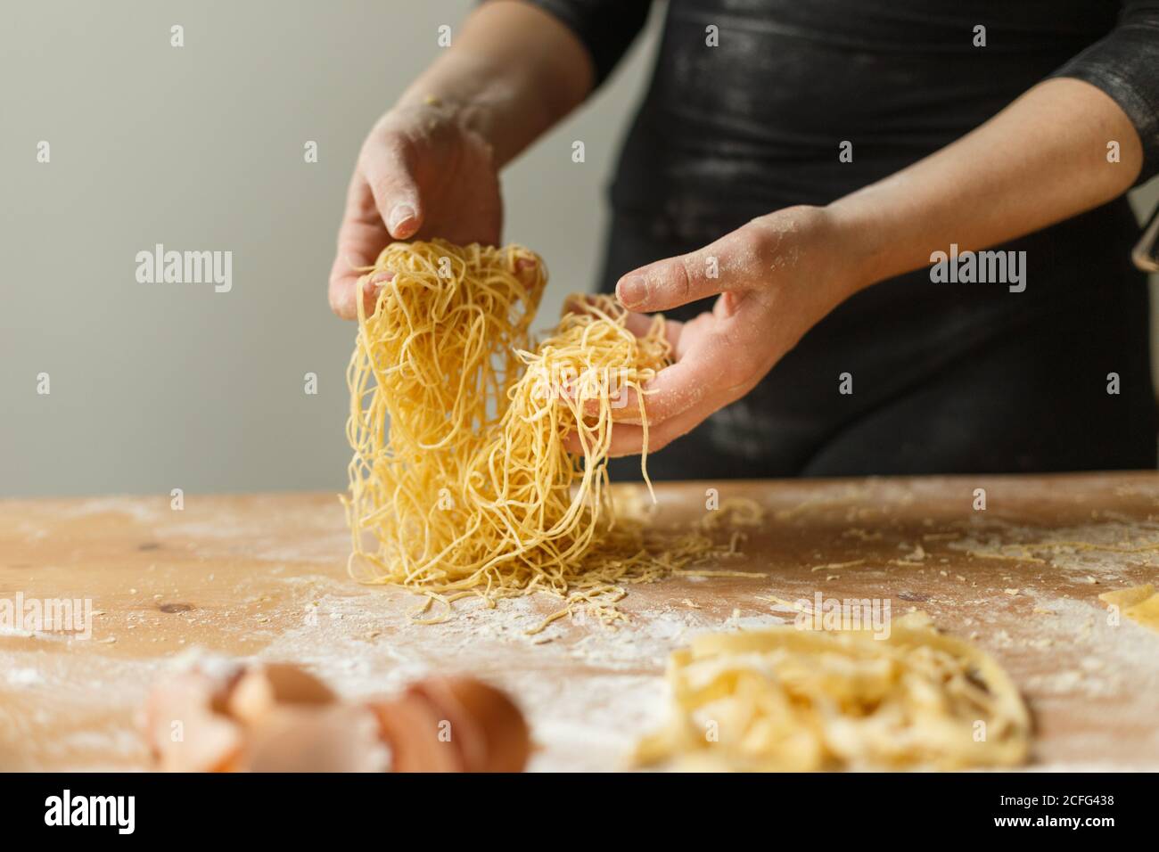 Woman holding cutting thin strips of pasta in hands while preparing ...