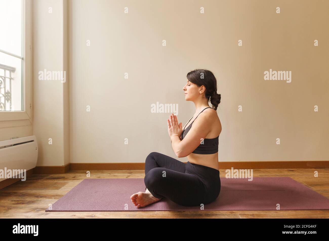 female sitting on mat with closed eyes and Namaste gesture while ...