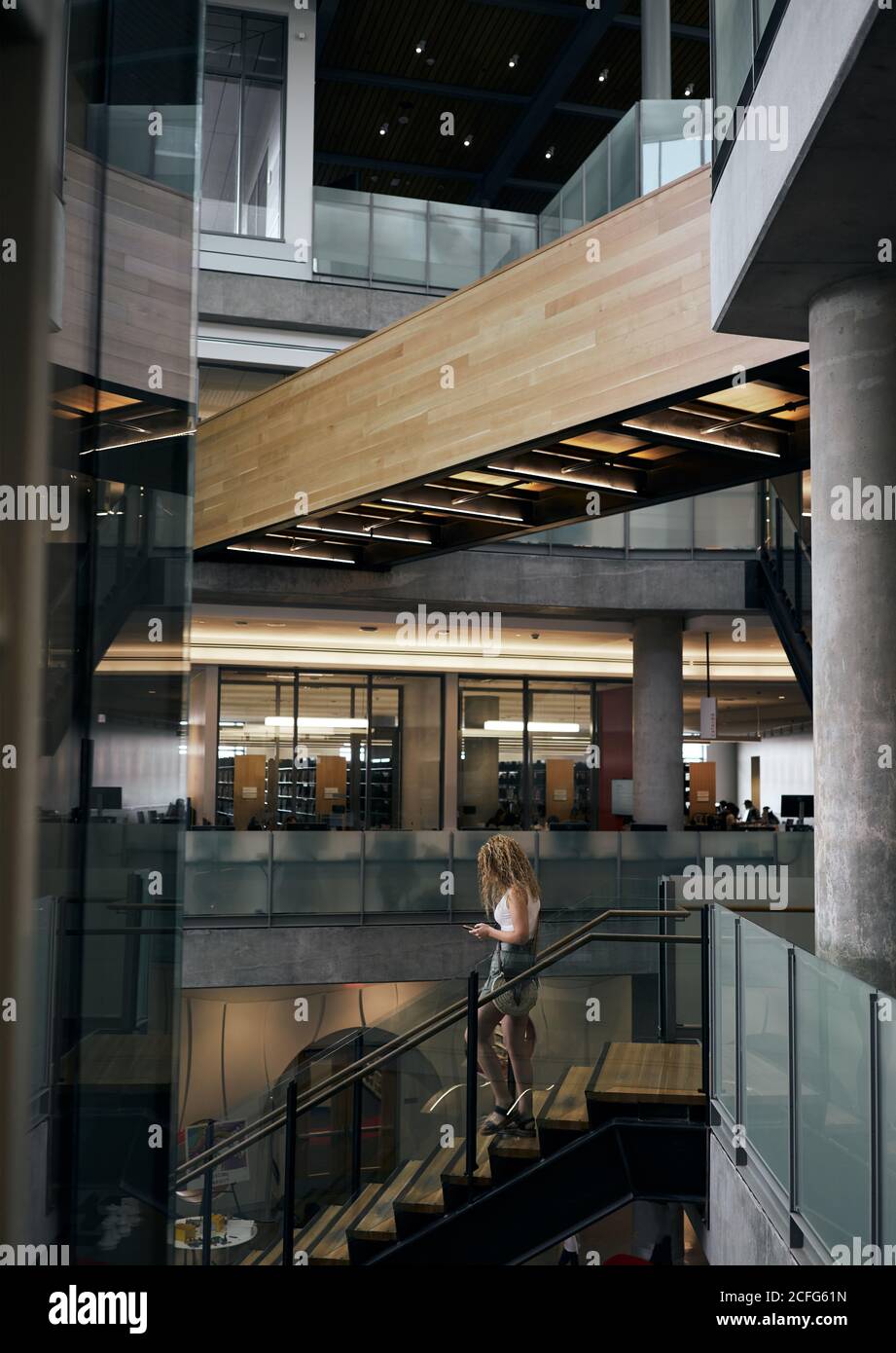 Side view of casual Woman moving down stairways in building of ...