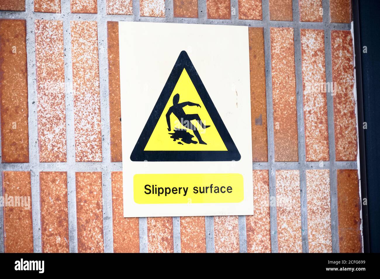 Slippery surface wall sign with yellow and black symbol Stock Photo - Alamy