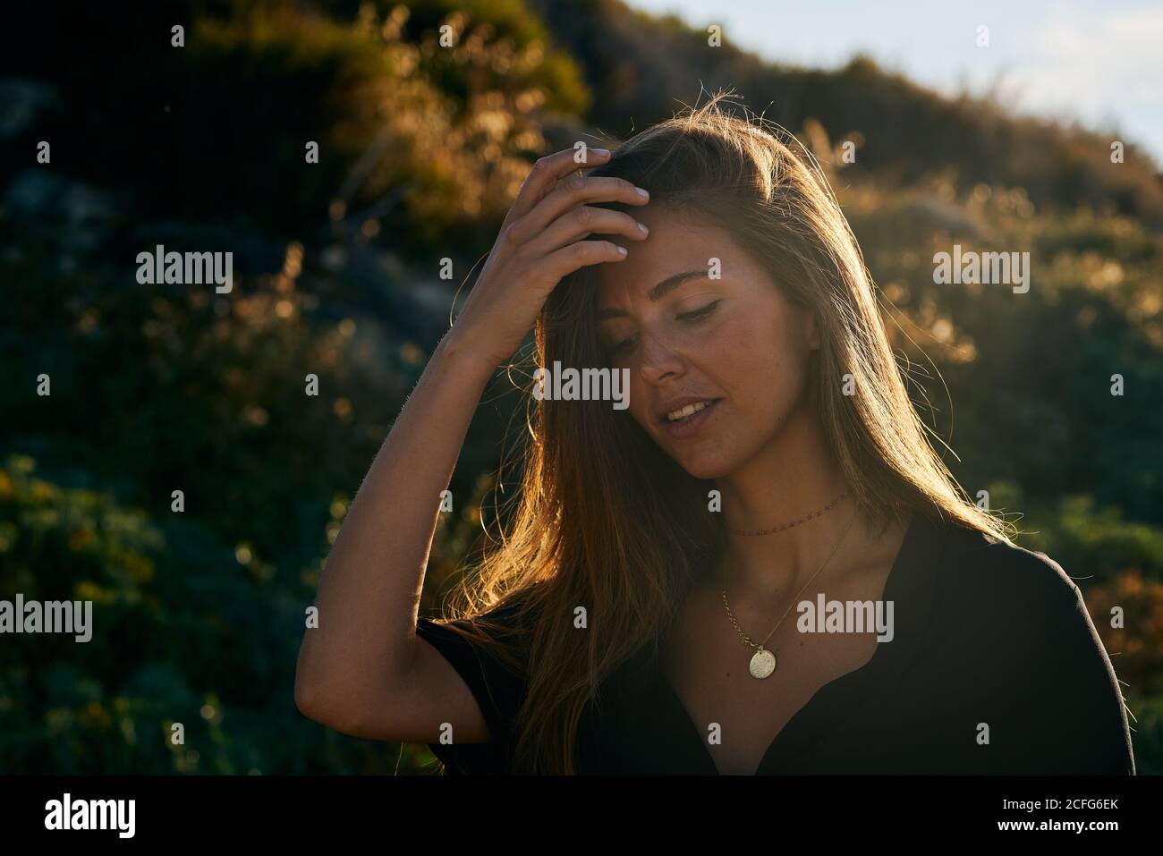 Young beautiful female model smiling and looking down in nature on ...