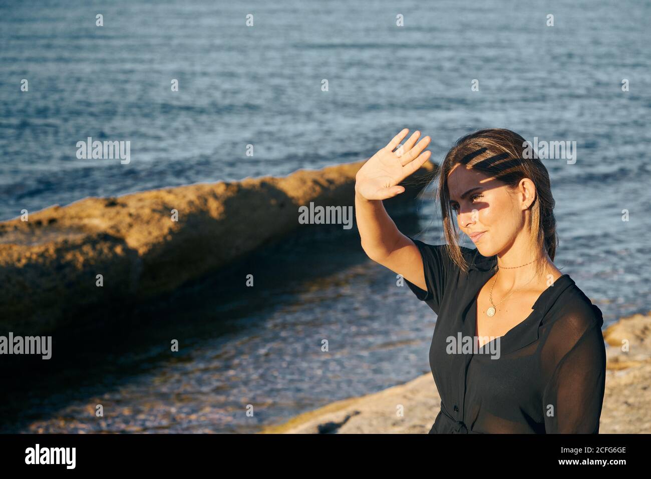 Young beautiful female model enjoying sun covering face of sun on beach ...