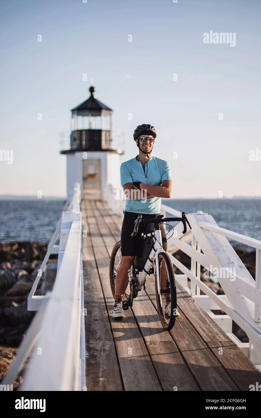 male cyclist poses with bike in front of lighthouse on Maine coast ...