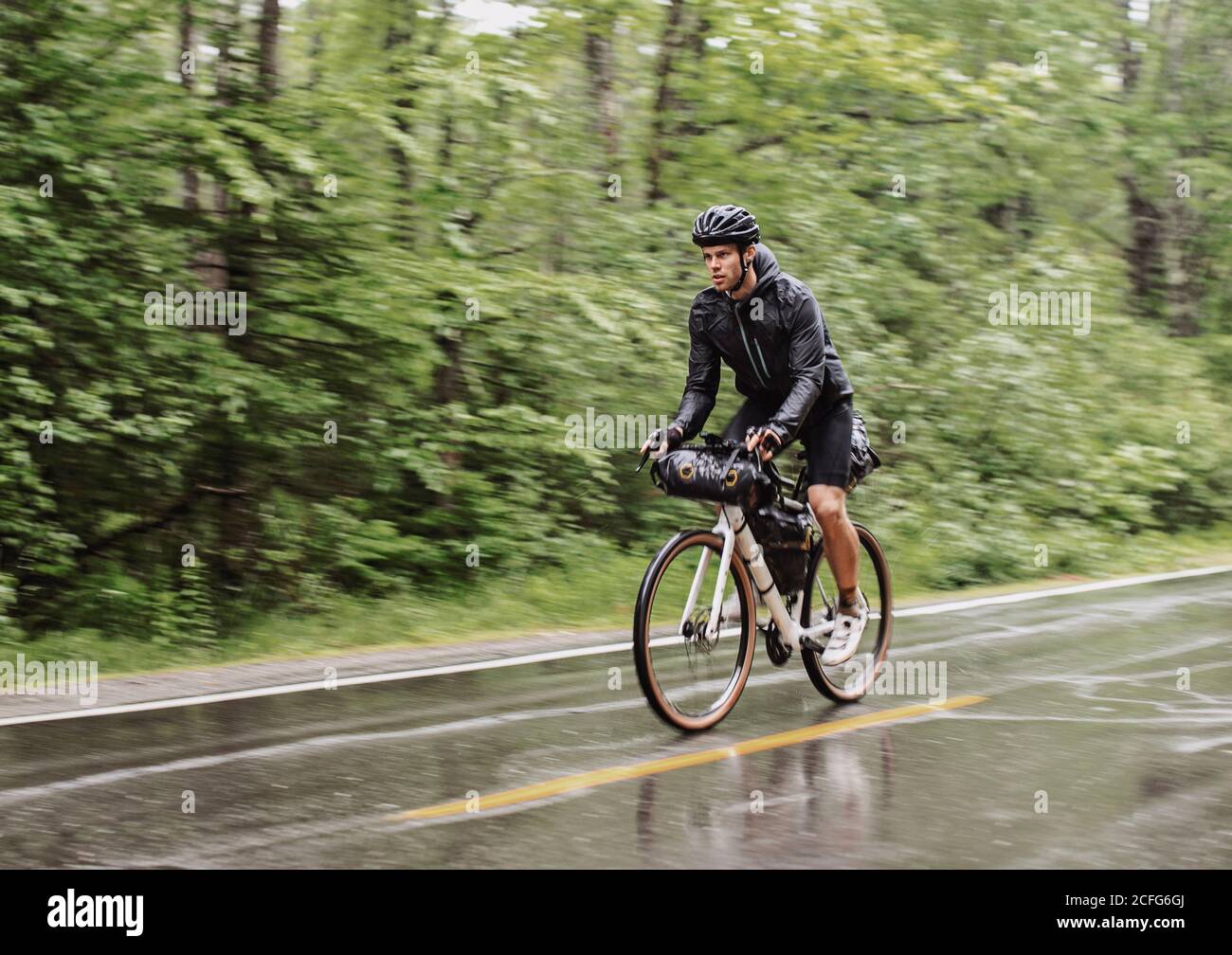 wet and soaked cyclist rides in pouring rain on road in Boothbay Maine ...