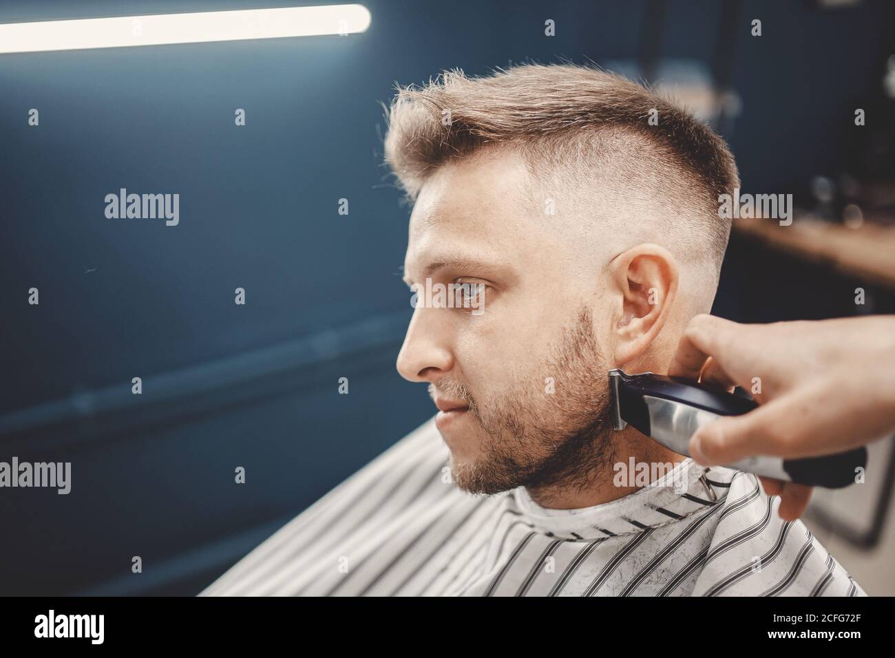 Barber shearing beard to man in barbershop framing hairline. electric ...