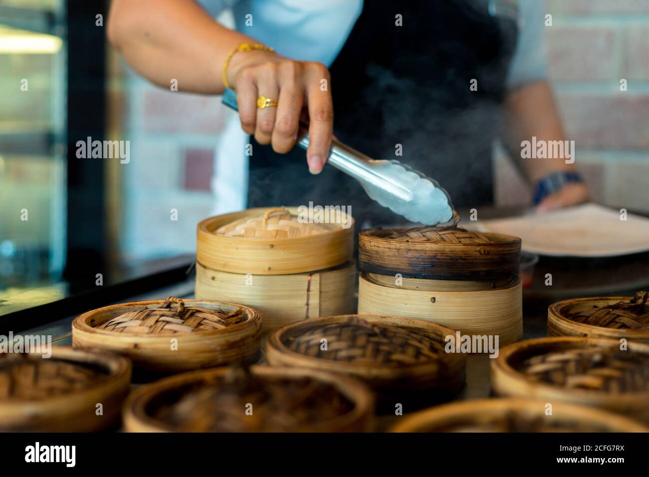 dim sum in bamboo steamer chinese cuisine. close up woman female hands ...