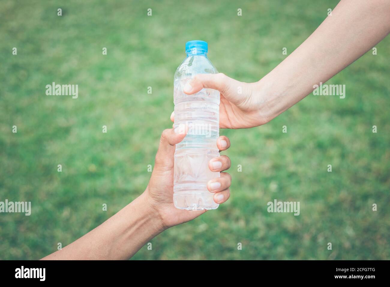 The man hand is sending a bottle of water and the lady hand is ...