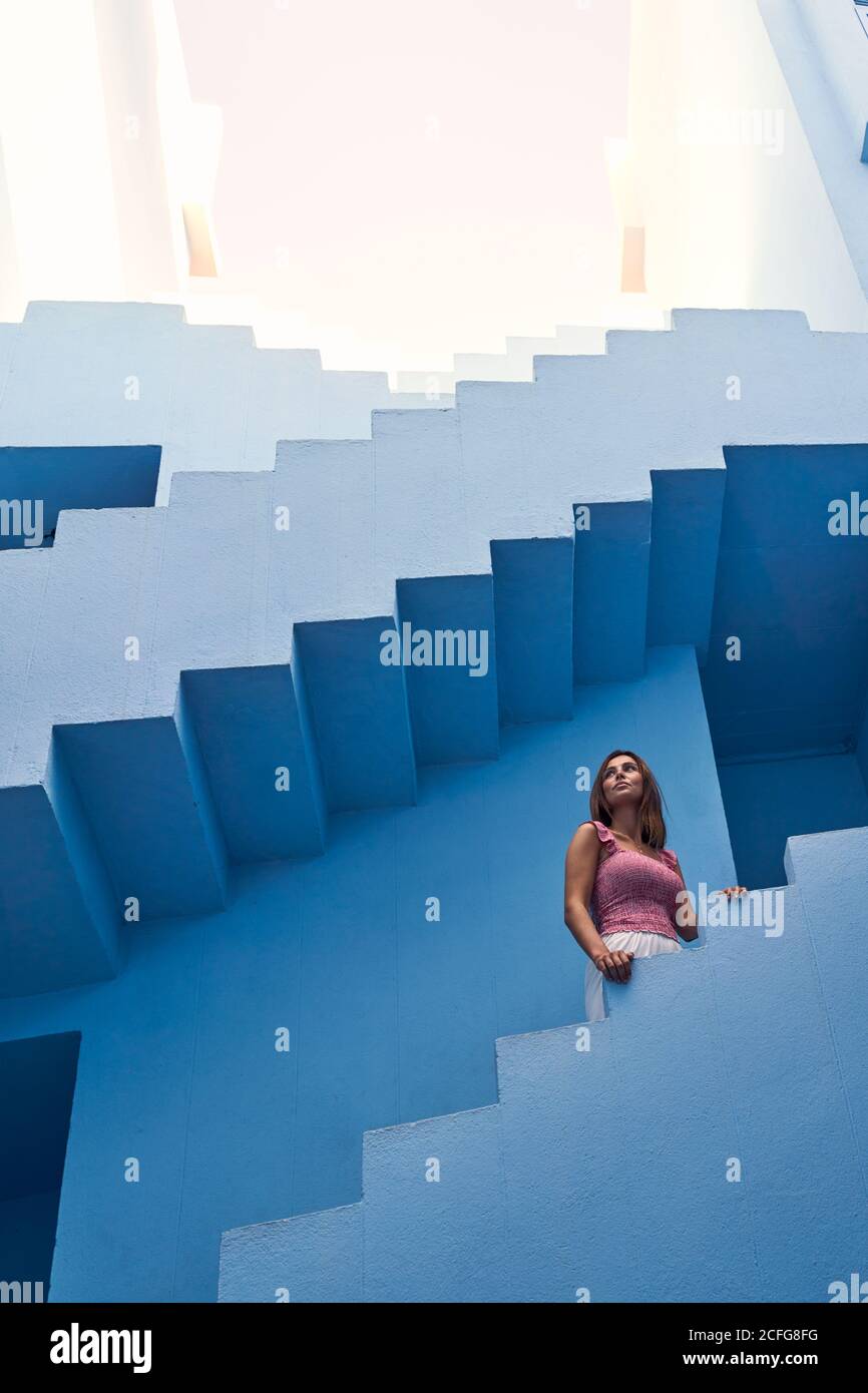 Side view of Woman walking upstairs on modern blue building looking ...