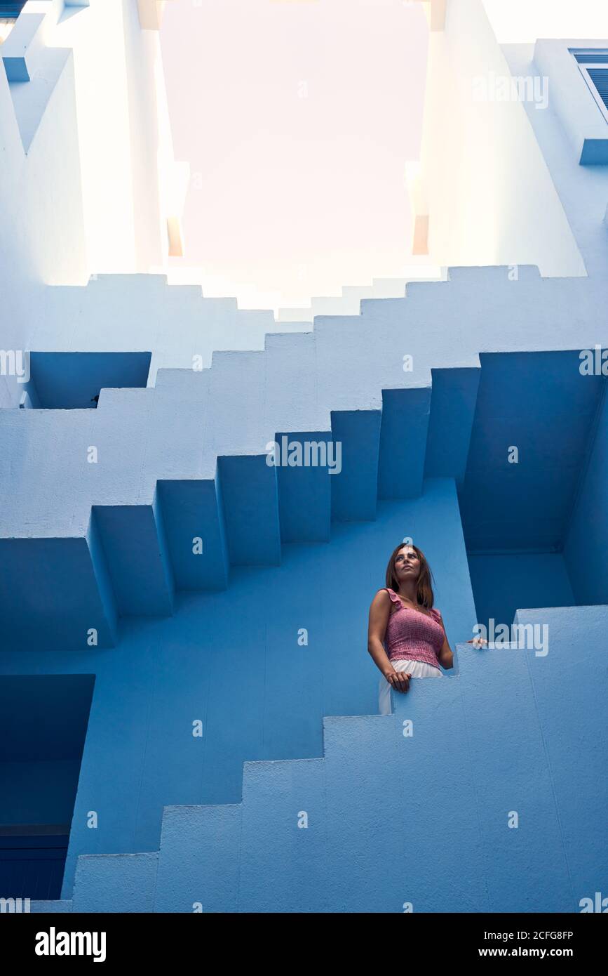 Side view of Woman walking upstairs on modern blue building looking ...