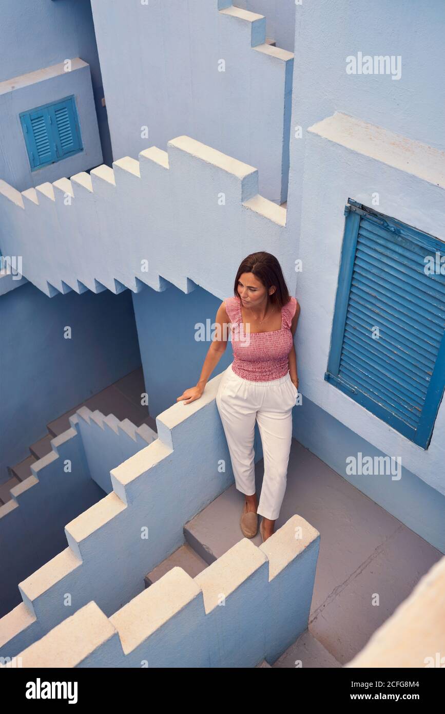 From above top view of young Woman walking upstairs on modern blue ...