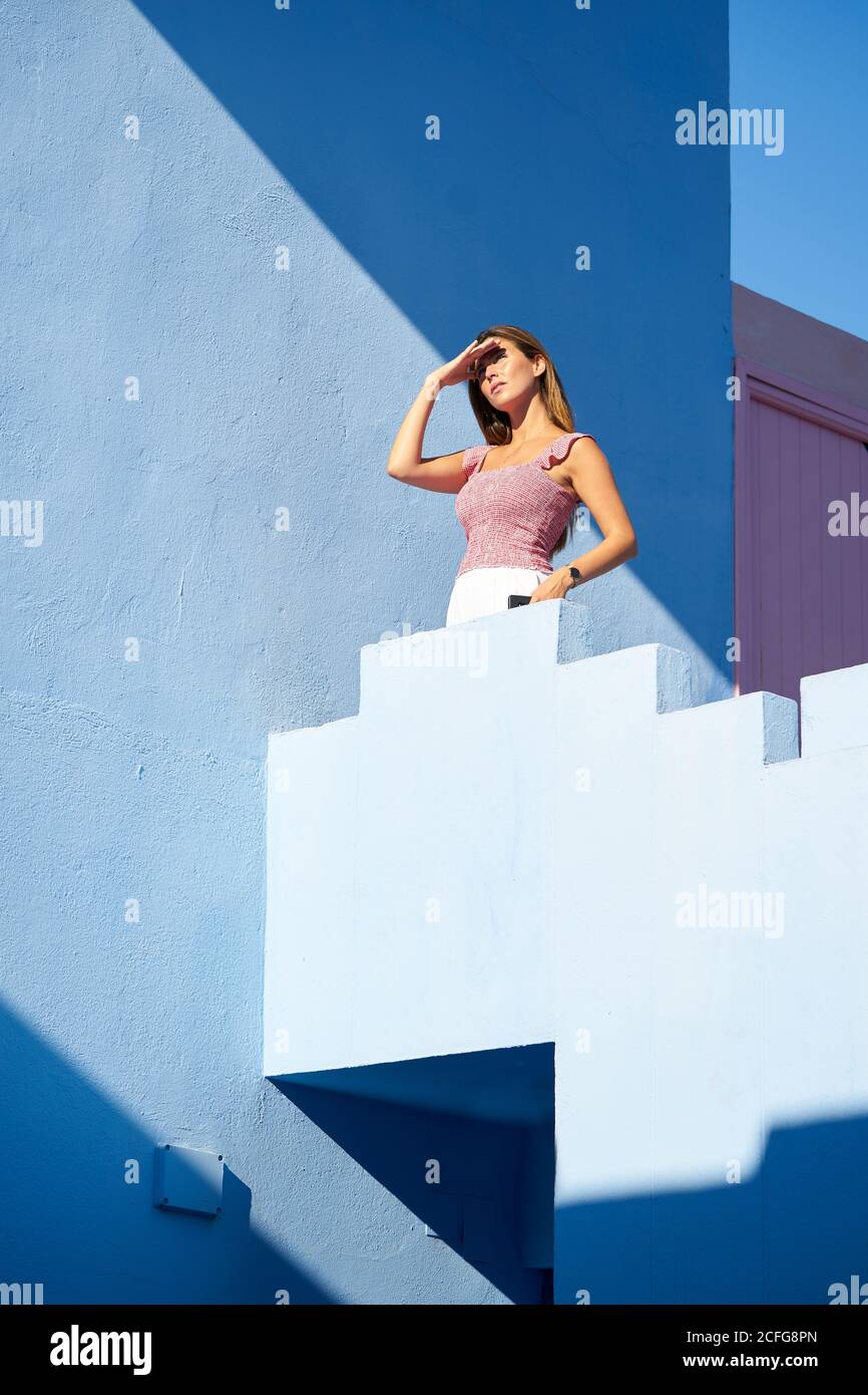From below Woman standing on the top of a blue building and looking ...