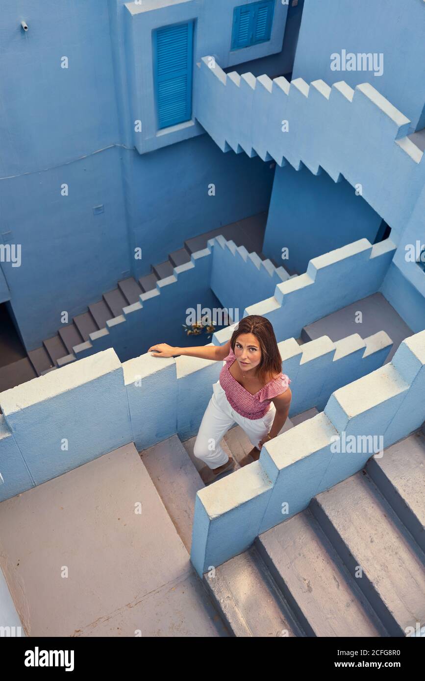 From above top view of young Woman walking upstairs on modern blue ...