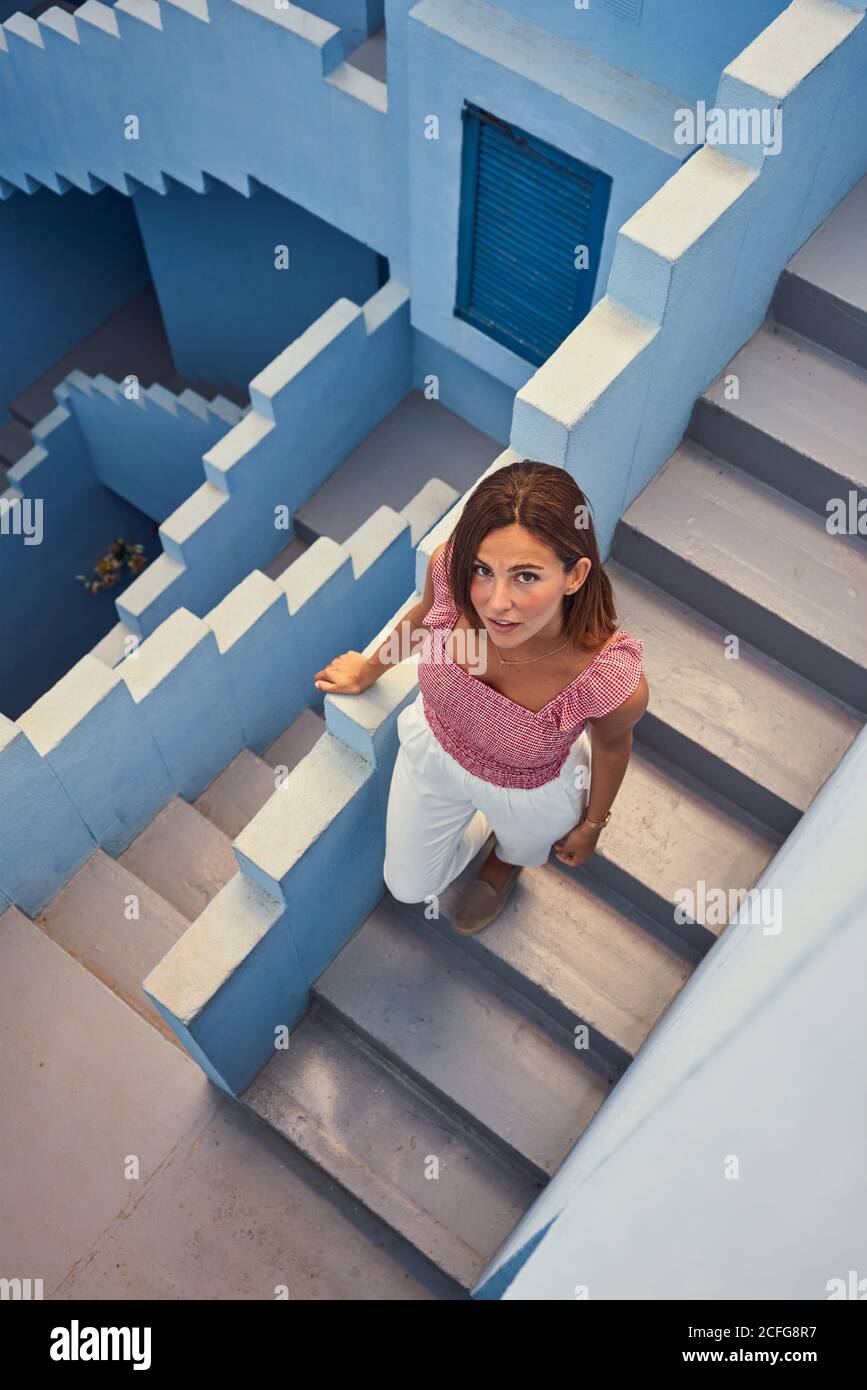 From above top view of young Woman walking upstairs on modern blue ...
