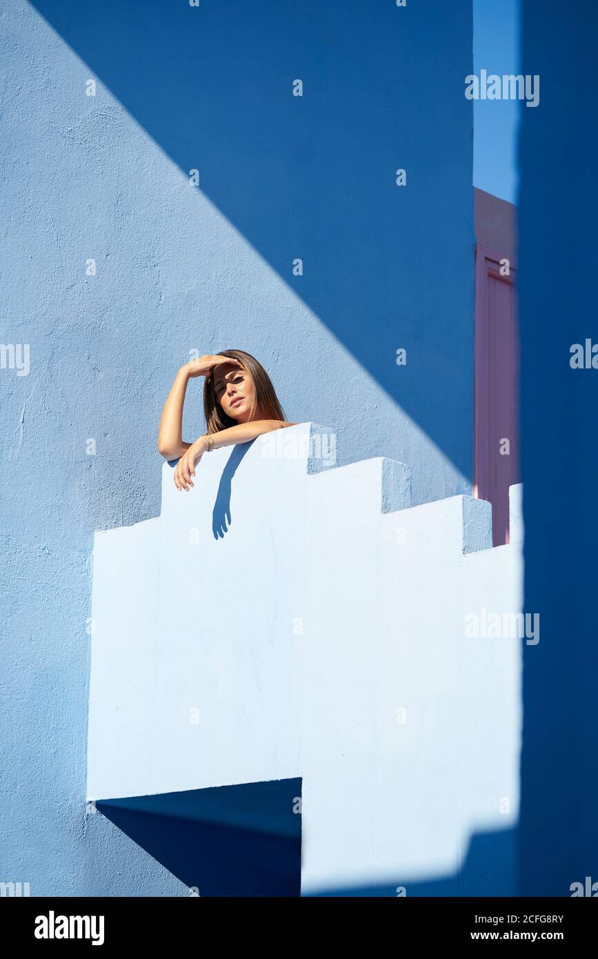 From below Woman standing on the top of a blue building and looking at ...