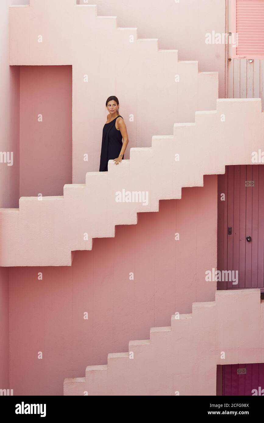 Side view of Woman walking downstairs on modern pink building Stock ...