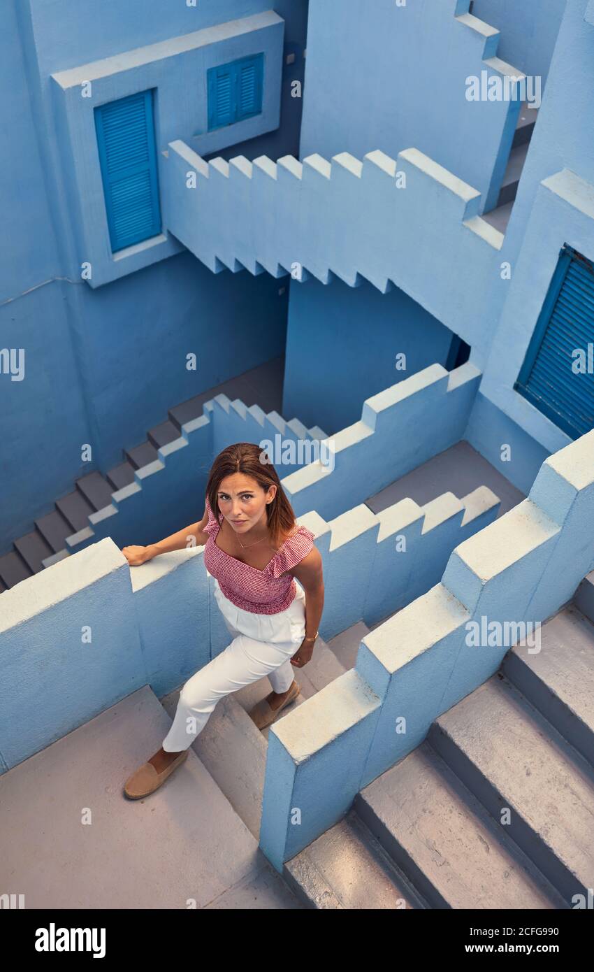 From above top view of young Woman walking upstairs on modern blue ...
