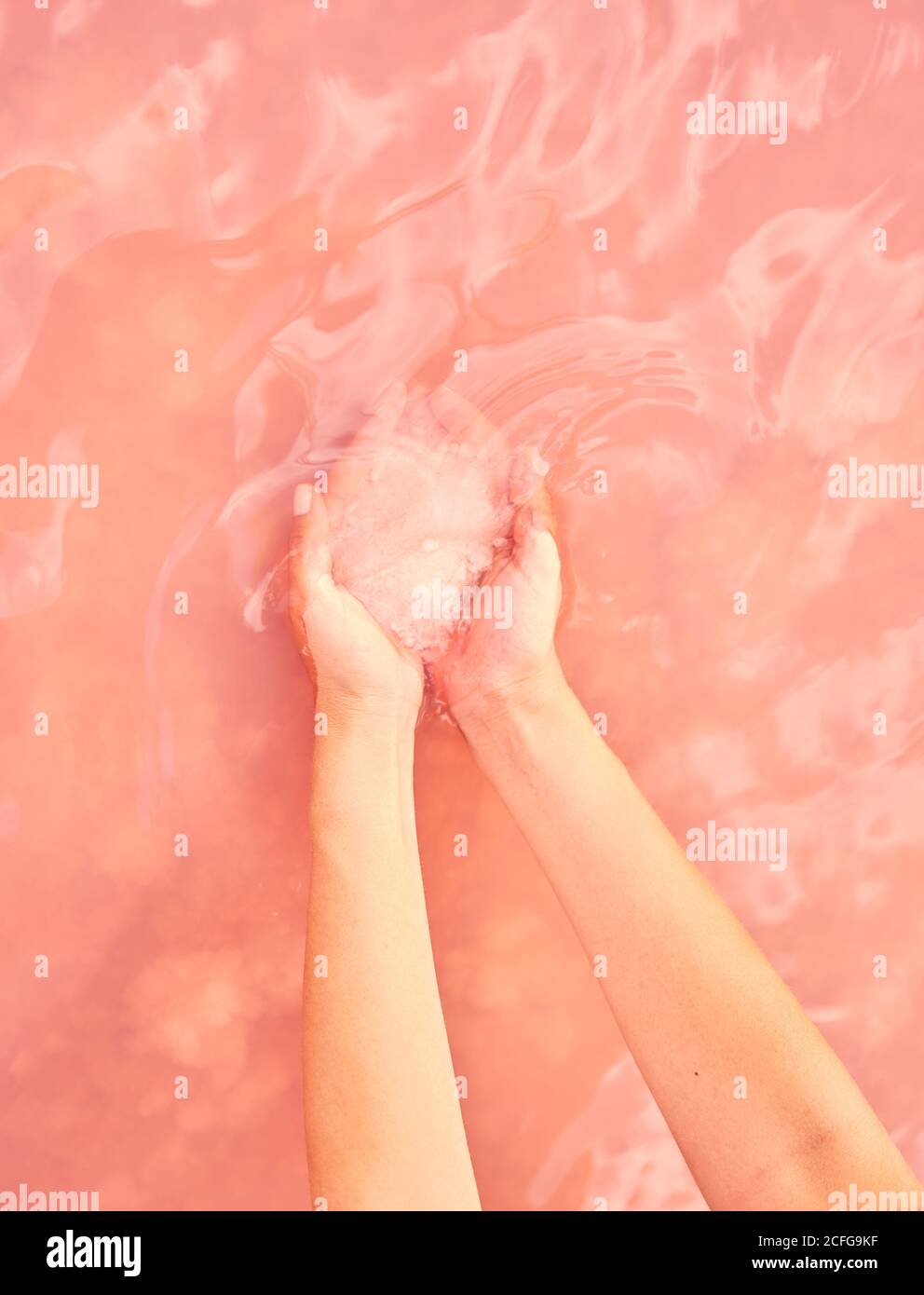 Female holding healing salt pile in pink water Stock Photo - Alamy