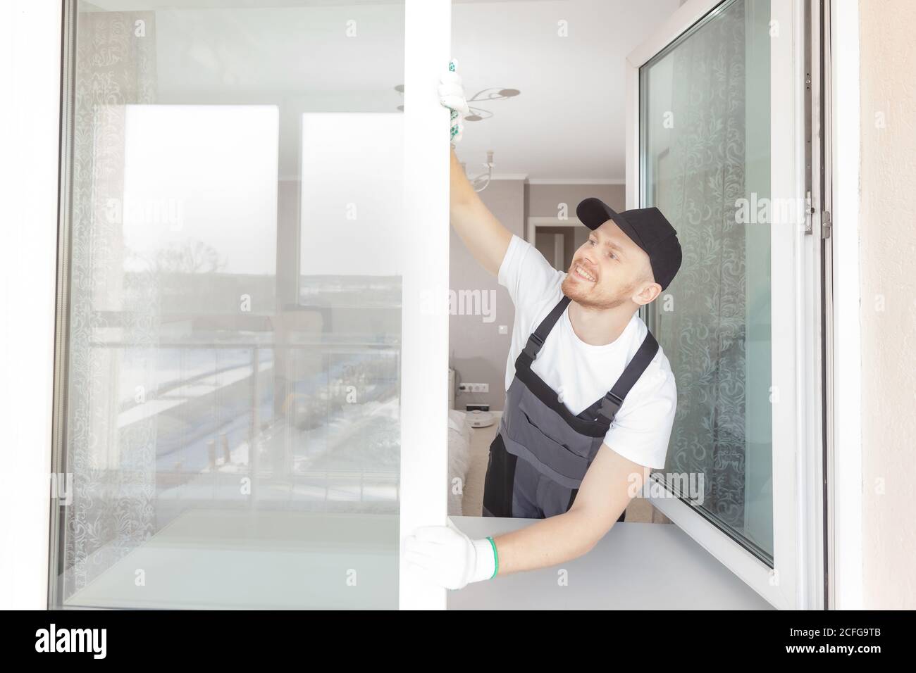 Worker man installs plastic windows and doors with double-glazed white ...