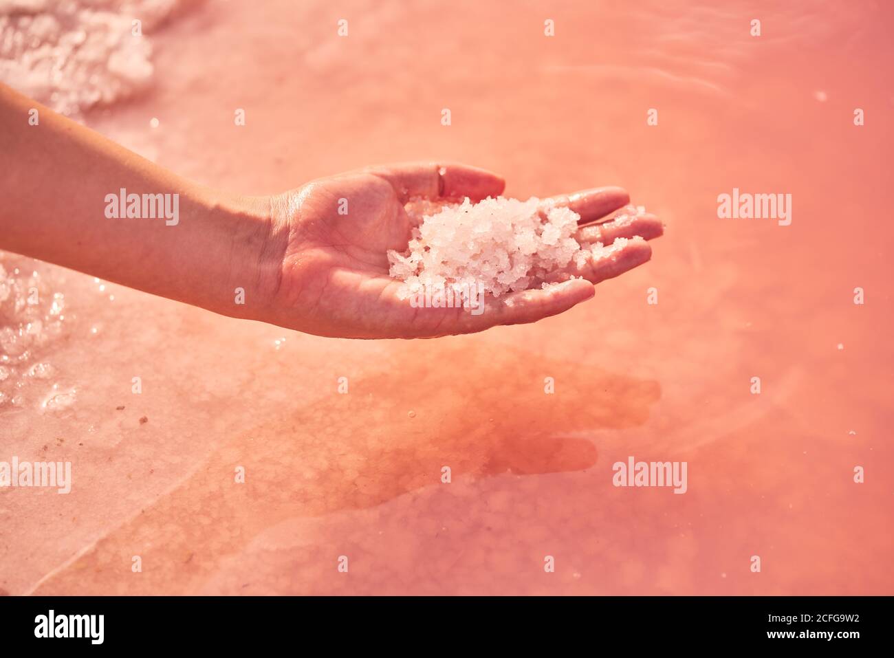 Female holding healing salt pile in pink water Stock Photo - Alamy