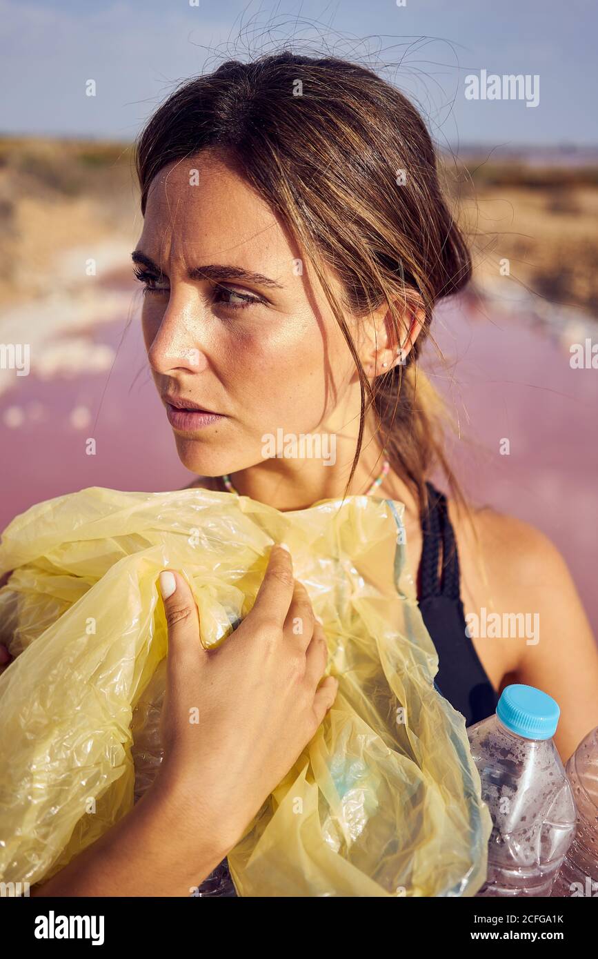 Concerned female in swimsuit collecting trash in natural lake Stock ...