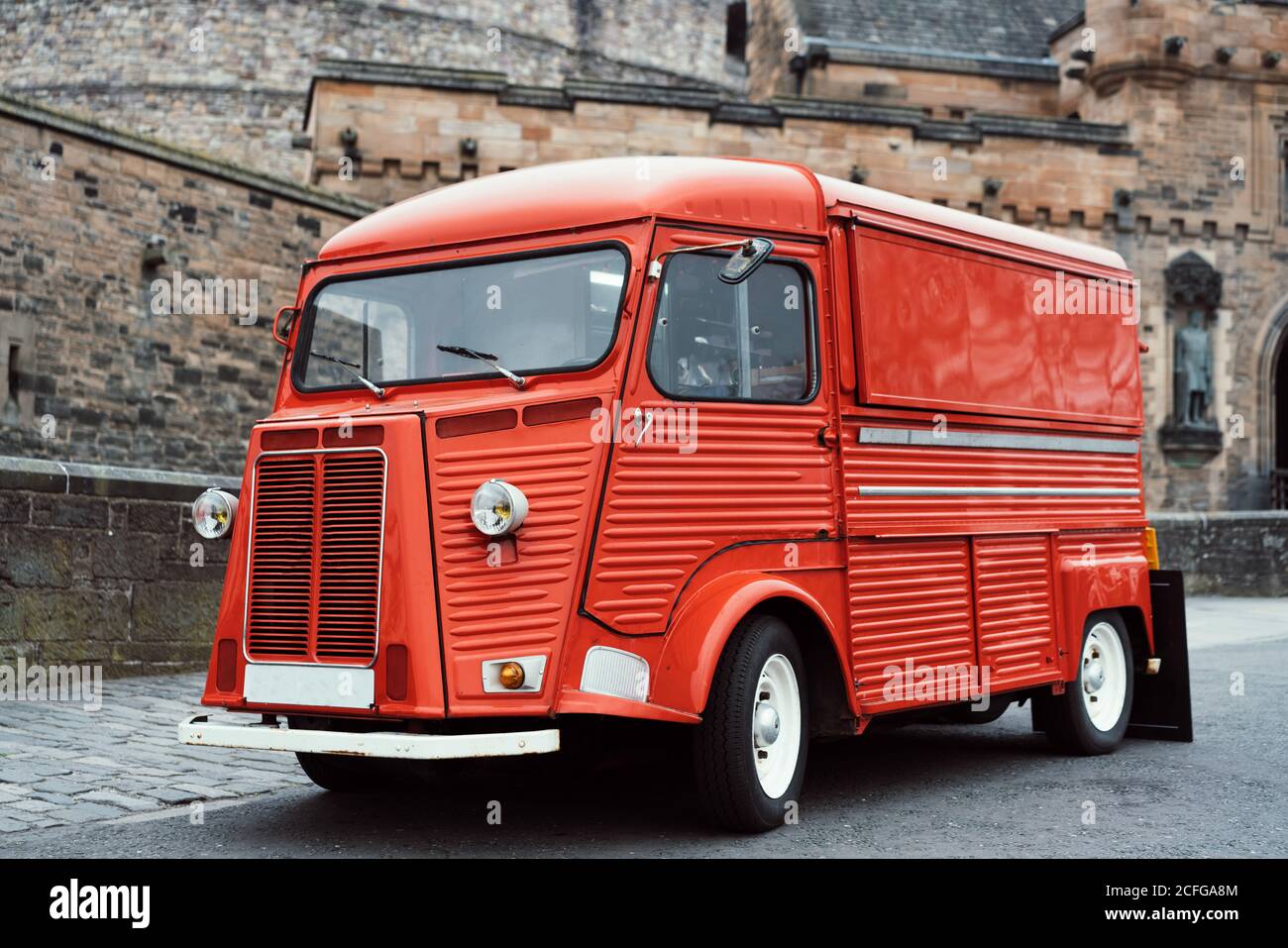 Retro red colored van on roadside with aged stone castle on background ...