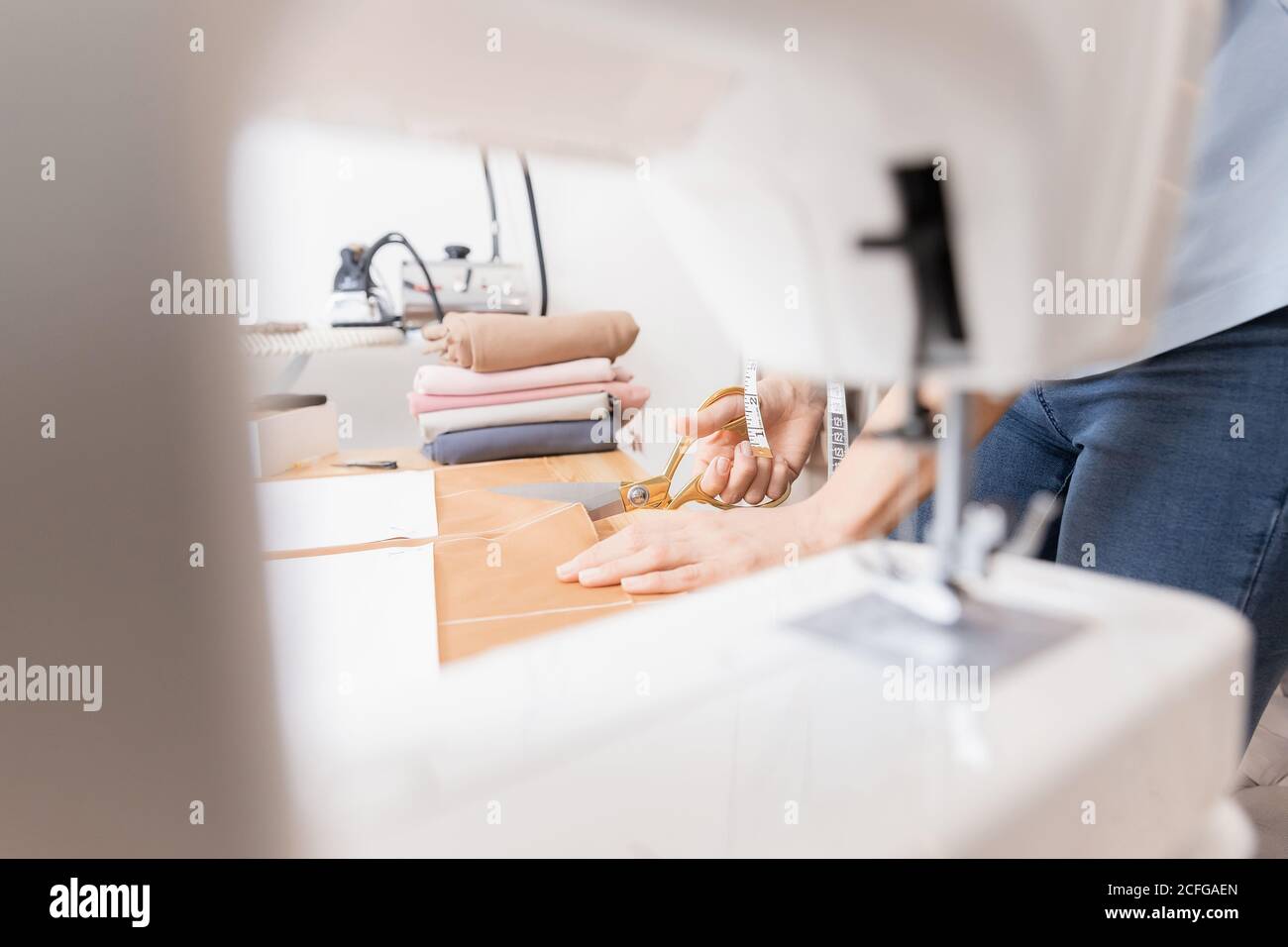 Workplace of seamstress tailor. Young female designer cuts out pattern ...