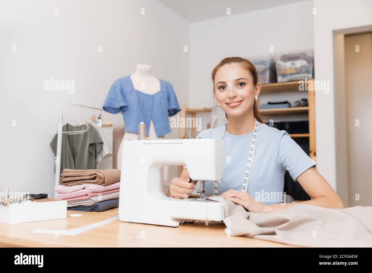 Seamstress young woman working sewing machine for production of clothes ...